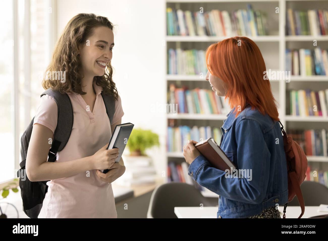 Two happy college mate girls meeting in campus library Stock Photo - Alamy