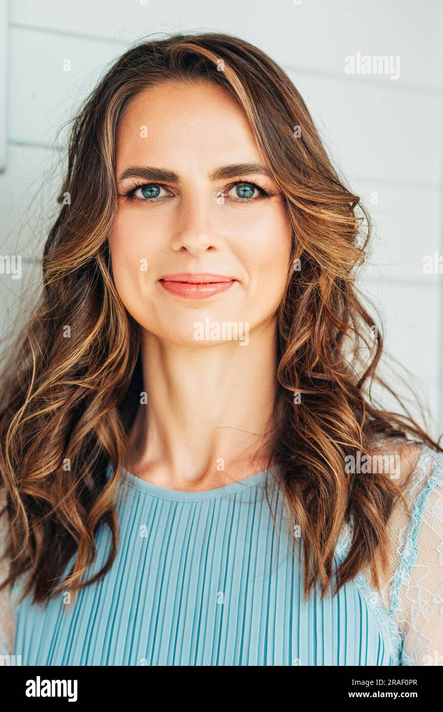 Outdoor Portrait Of Beautiful Woman With Curly Hair Wearing Blue Dress