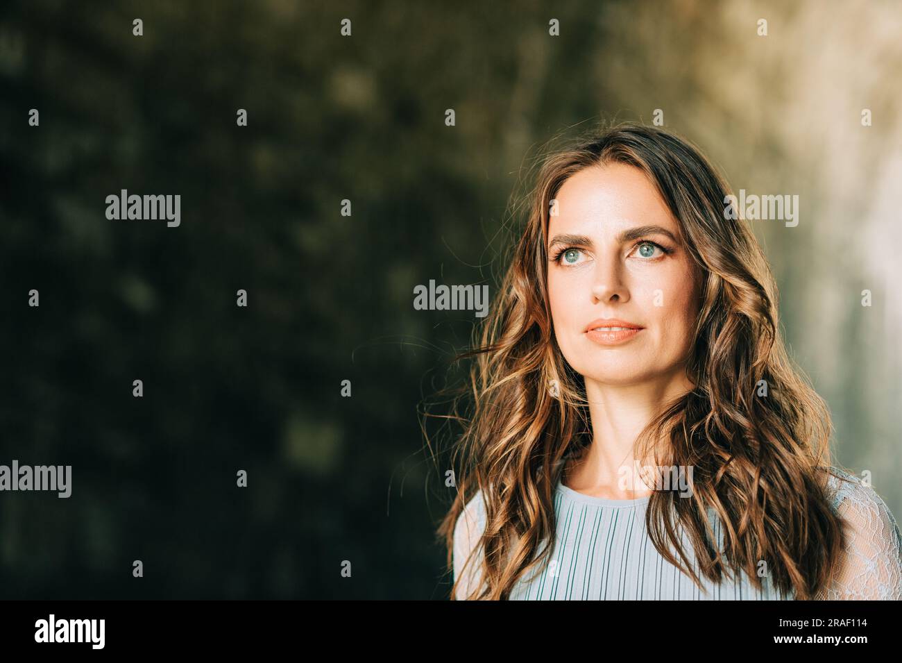Outdoor Portrait Of Beautiful Woman With Curly Hair Wearing Blue Dress