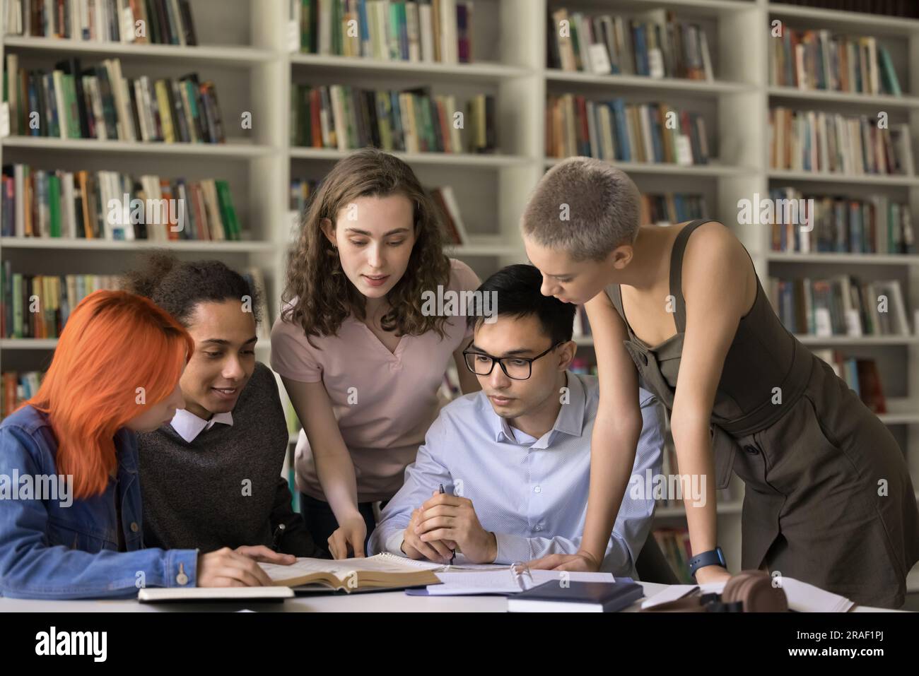 College classmates reading textbook in campus library together Stock ...