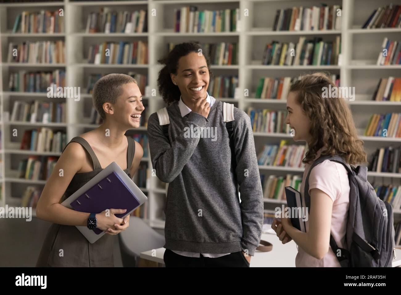 Cheerful diverse student girls and guy talking in college library Stock ...