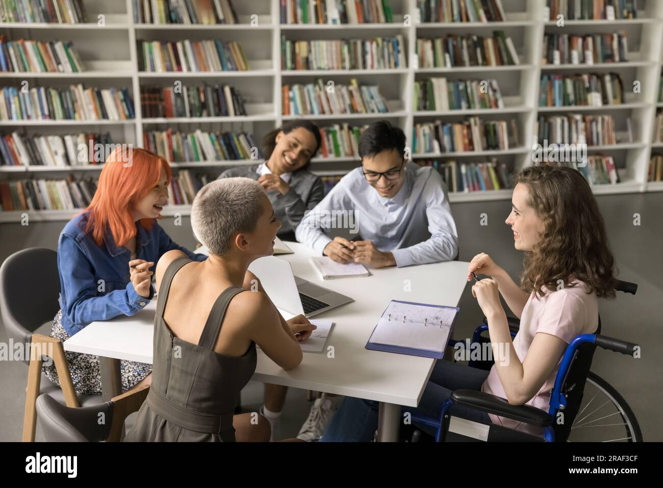 Group of students and classmate with disability studying in library ...