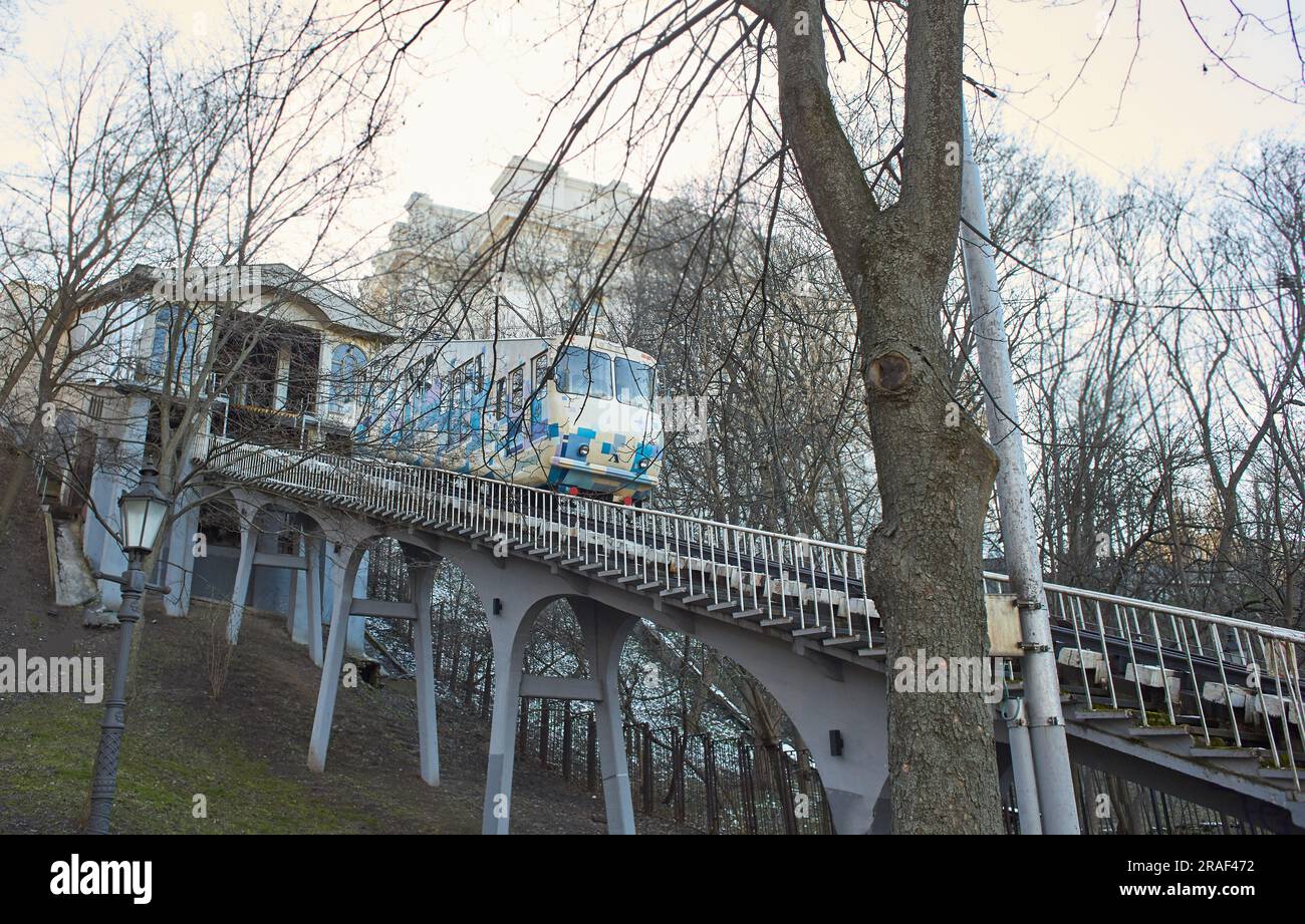 A blue and white cable funicular rises on rails along the slope ...