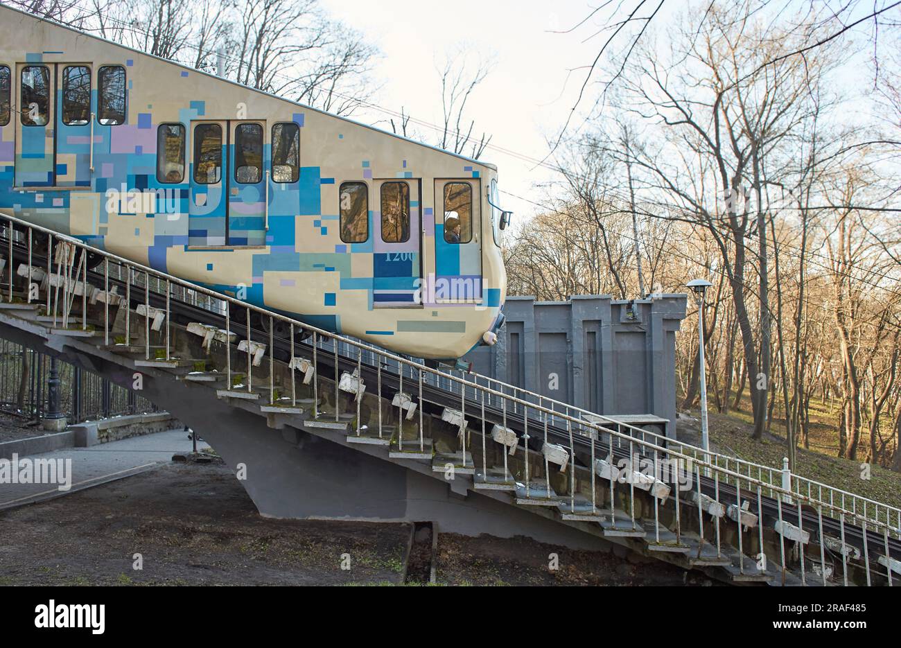A blue and white cable funicular rises on rails along the slope ...