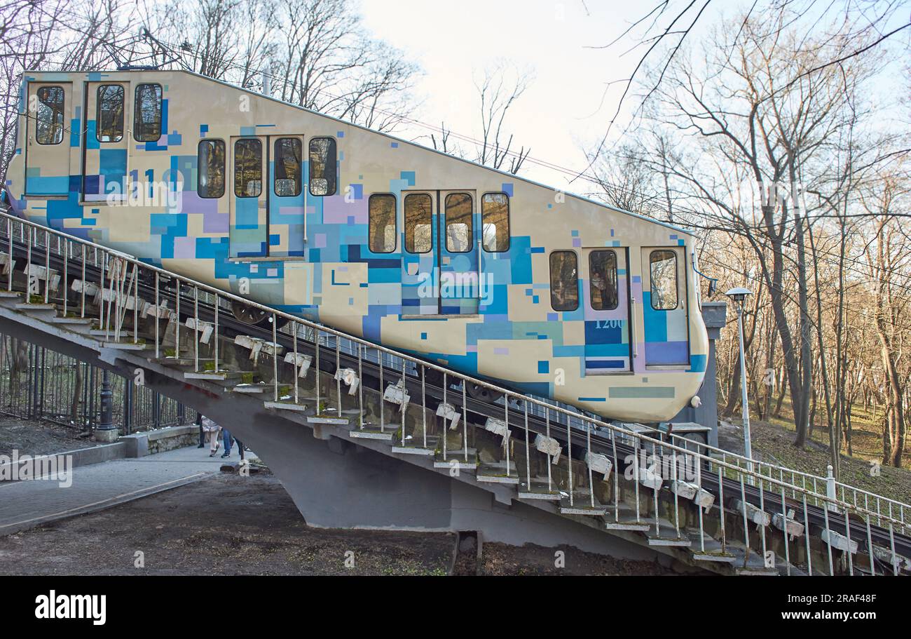 A blue and white cable funicular rises on rails along the slope ...