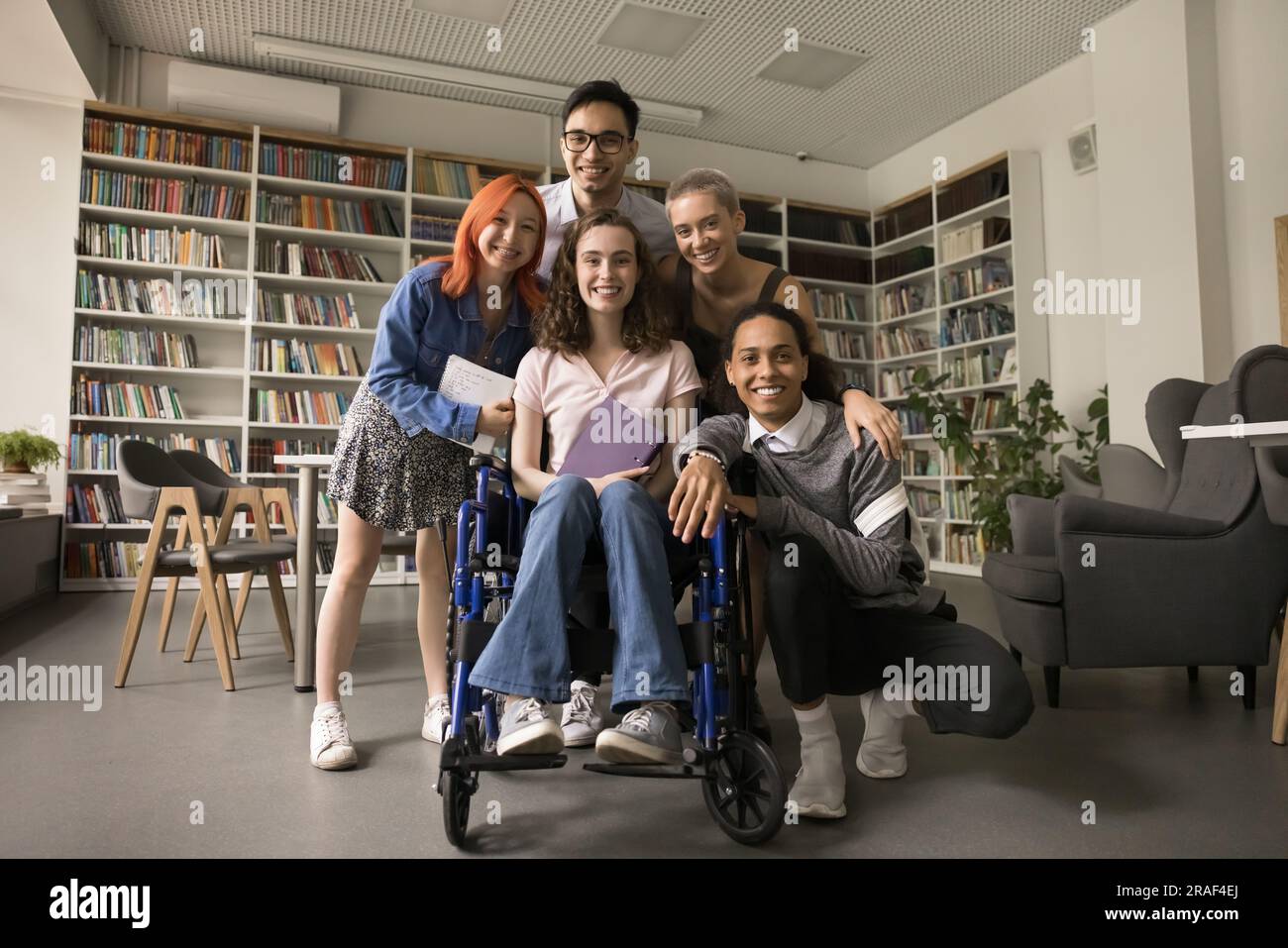 College student friends and classmate with disability posing in library ...