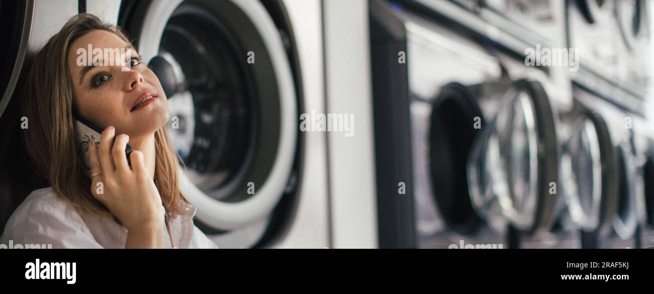 Young woman calling, waiting in a laundry room Stock Photo - Alamy