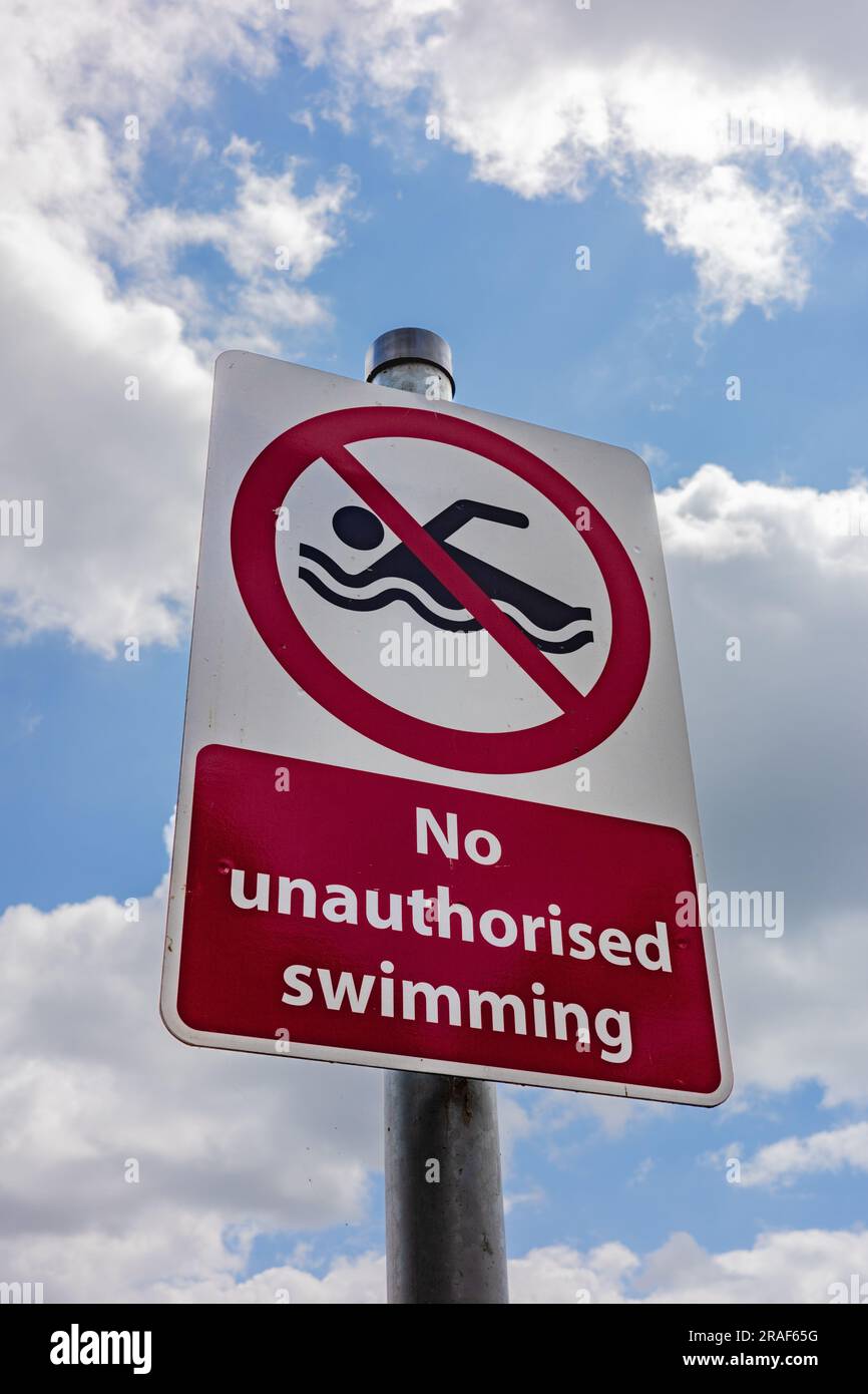 warning sign no unauthorised swimming in this area against a blue sky ...