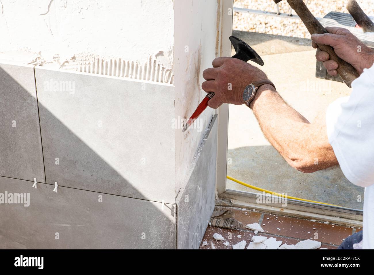the mason prepares the wall with a chisel before laying a ceramic tile ...