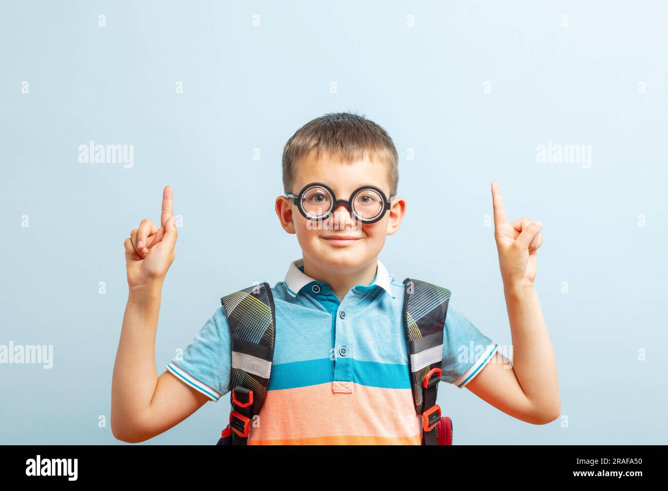 Happy school boy pointing fingers up showing something on blue ...
