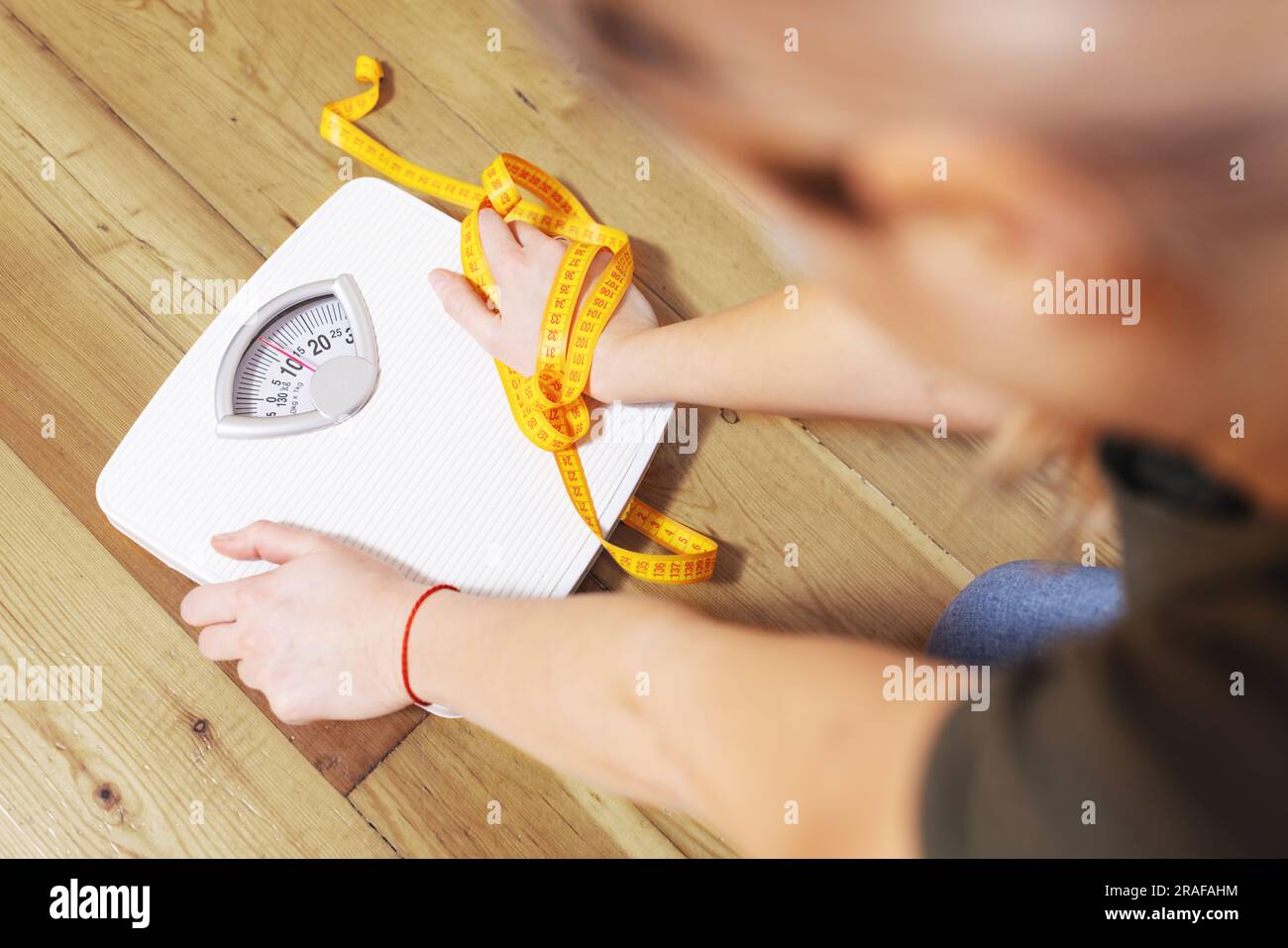 Depressed, frustrated and sad woman with a measuring tape looks at a ...