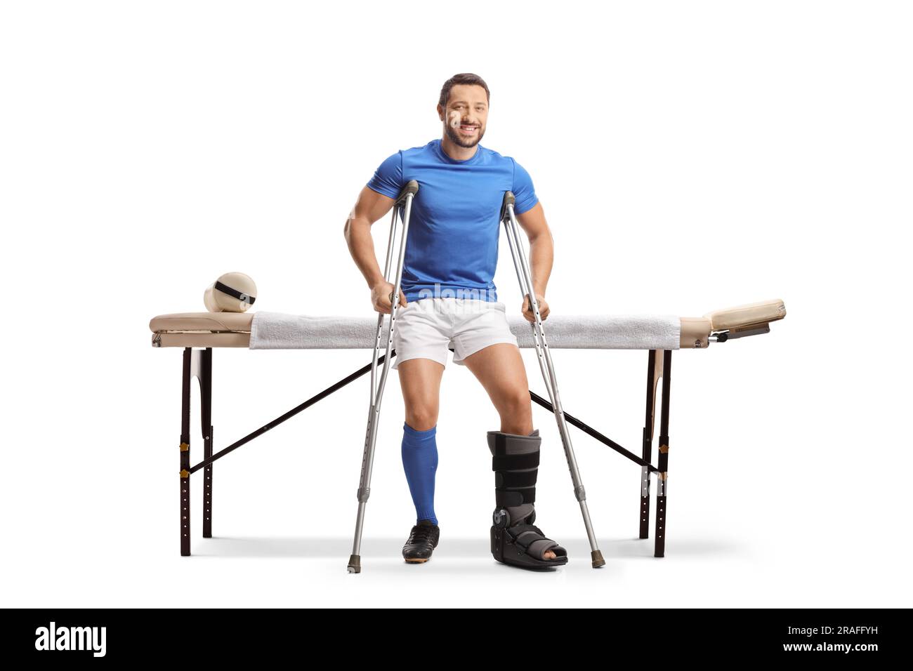 Football player with crutches sitting on a physical therapy bed ...