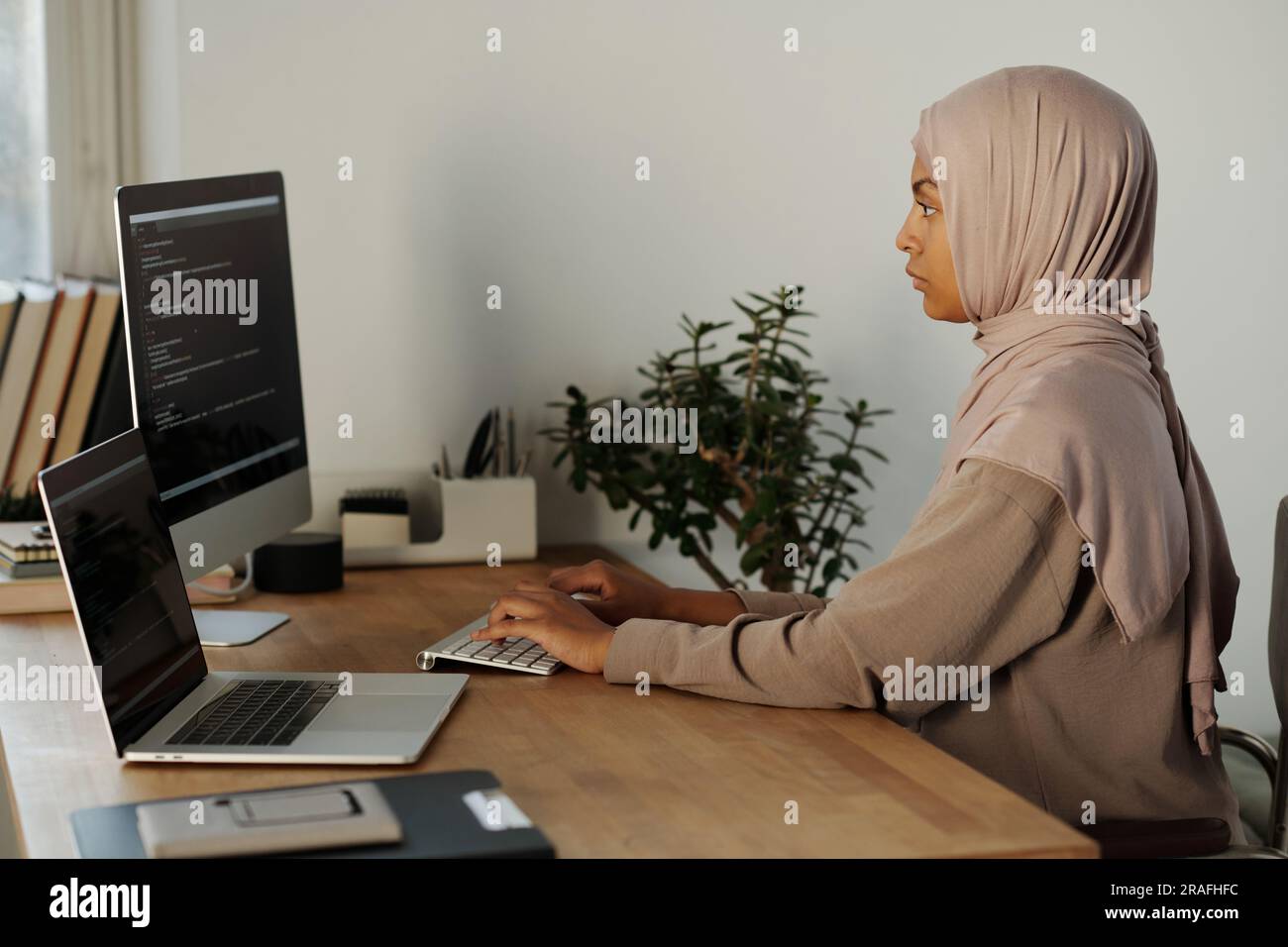 Young Muslim businesswoman in hijab decoding data on computer screen ...