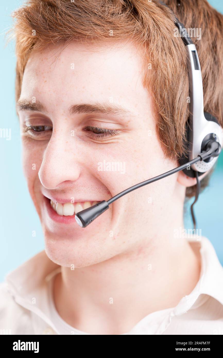 Young call center employee with red hair. Behind him, productivity ...