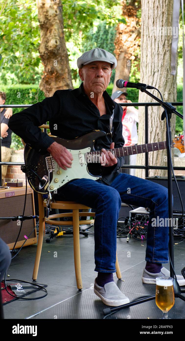 Guitarist and singer sitting down in front of a microphone on stage in ...