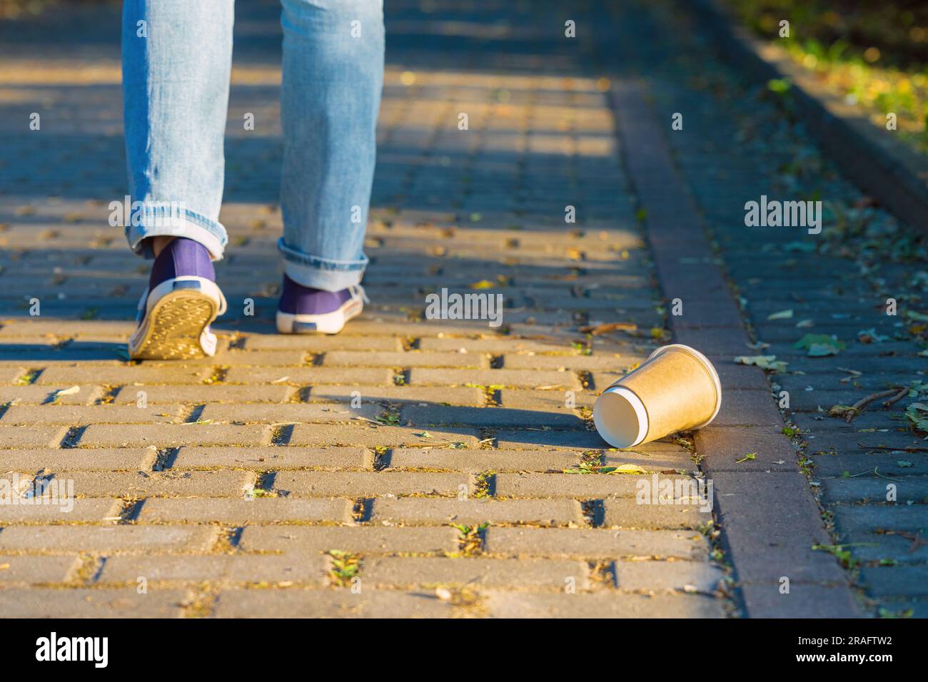 a man threw a glass of coffee on the street. man littering in the park ...