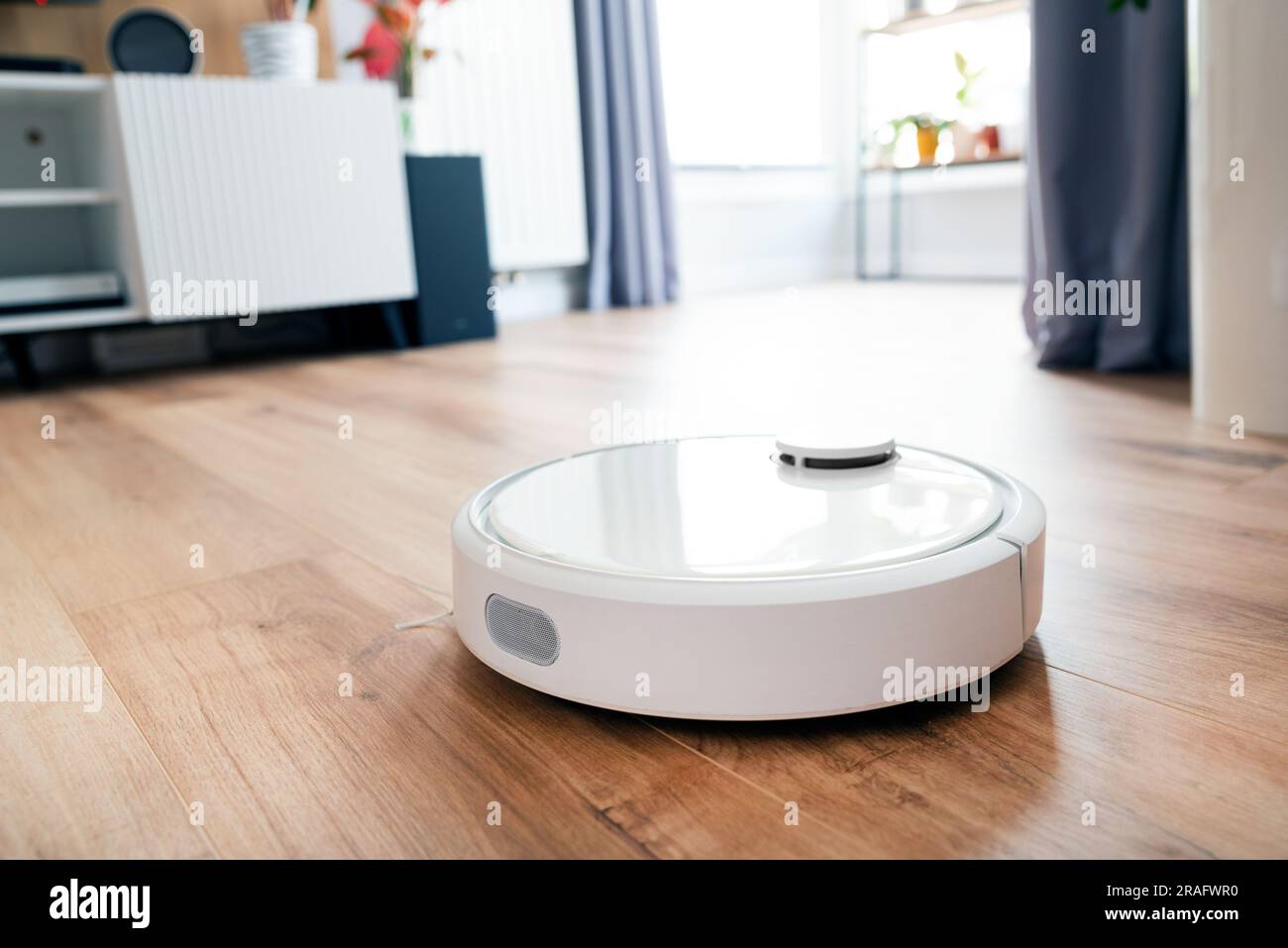 White robot vaccum cleaner on the floor in the living room, smart home ...