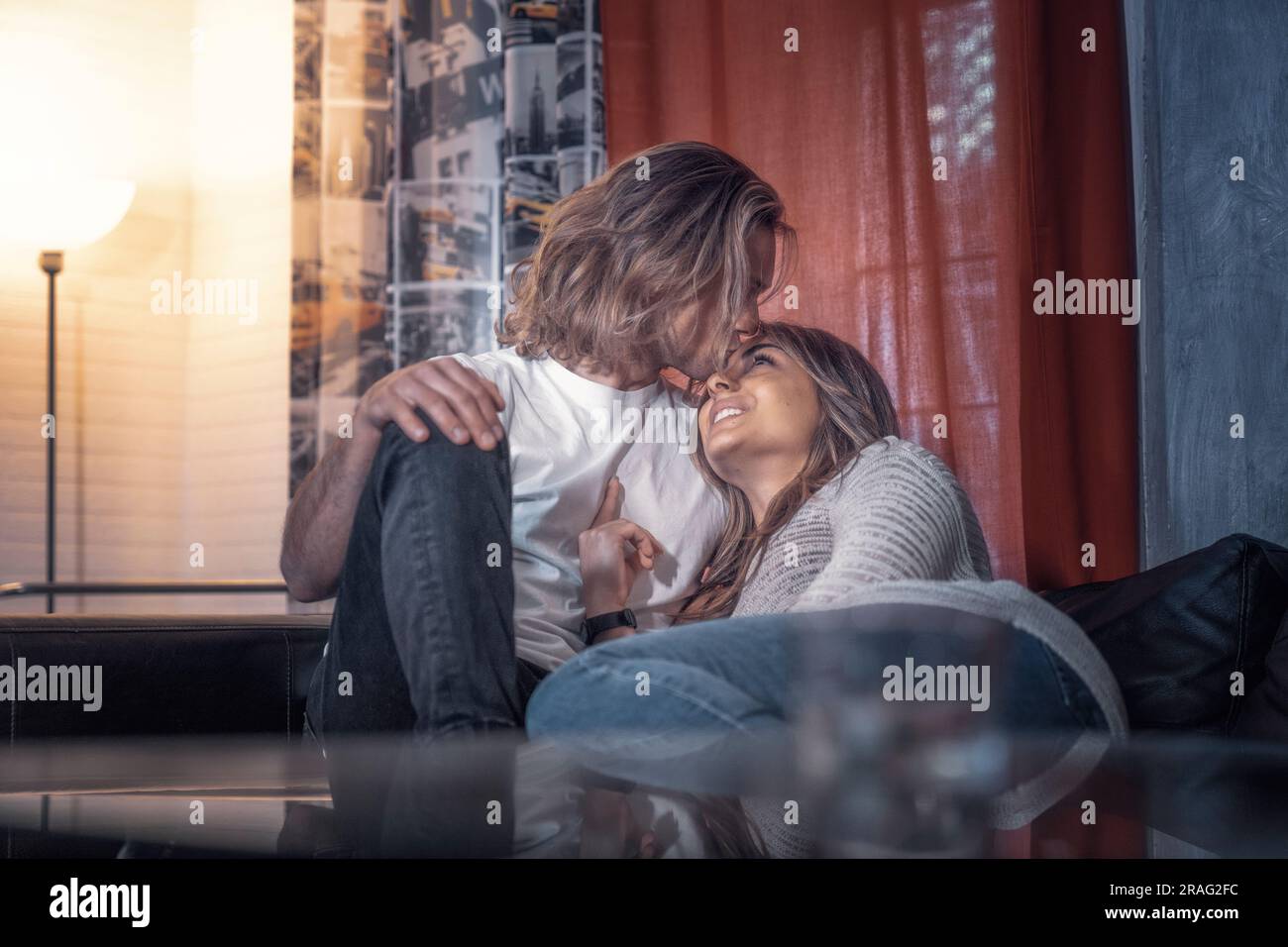 Inside house couple shooting sitting on sofa relaxing and smiling ...