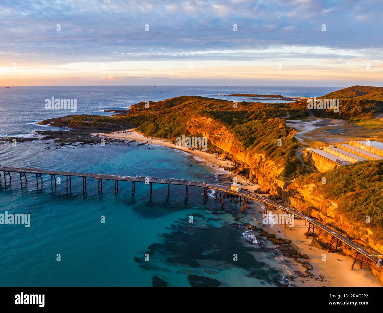 Sunrise seascape with cloud filled sky and the old coal loading jetty ...