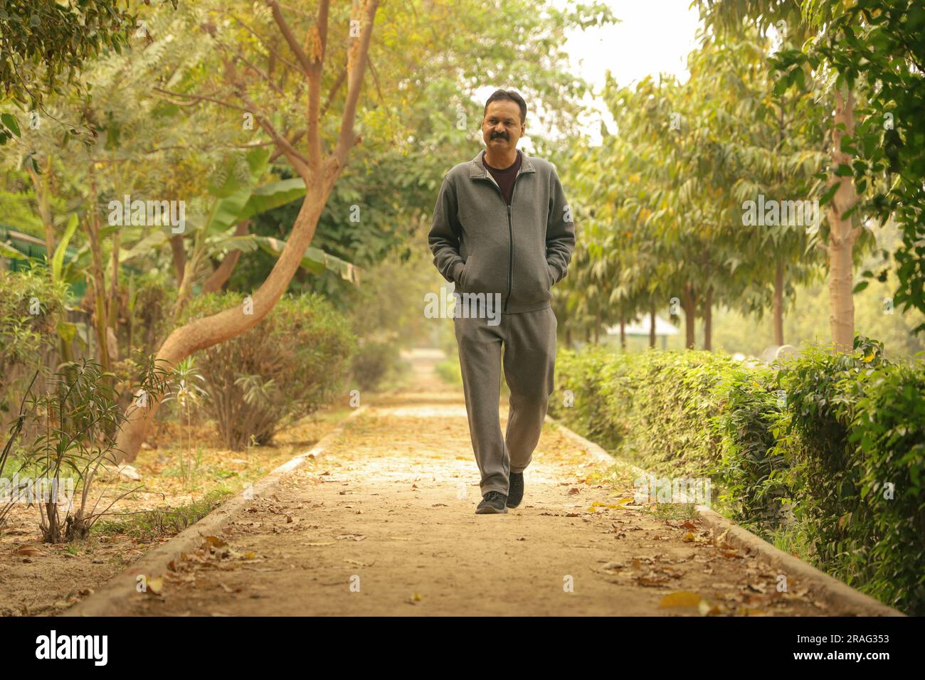 Happy Indian Old man jogging in the park on a Jogging track and trail ...
