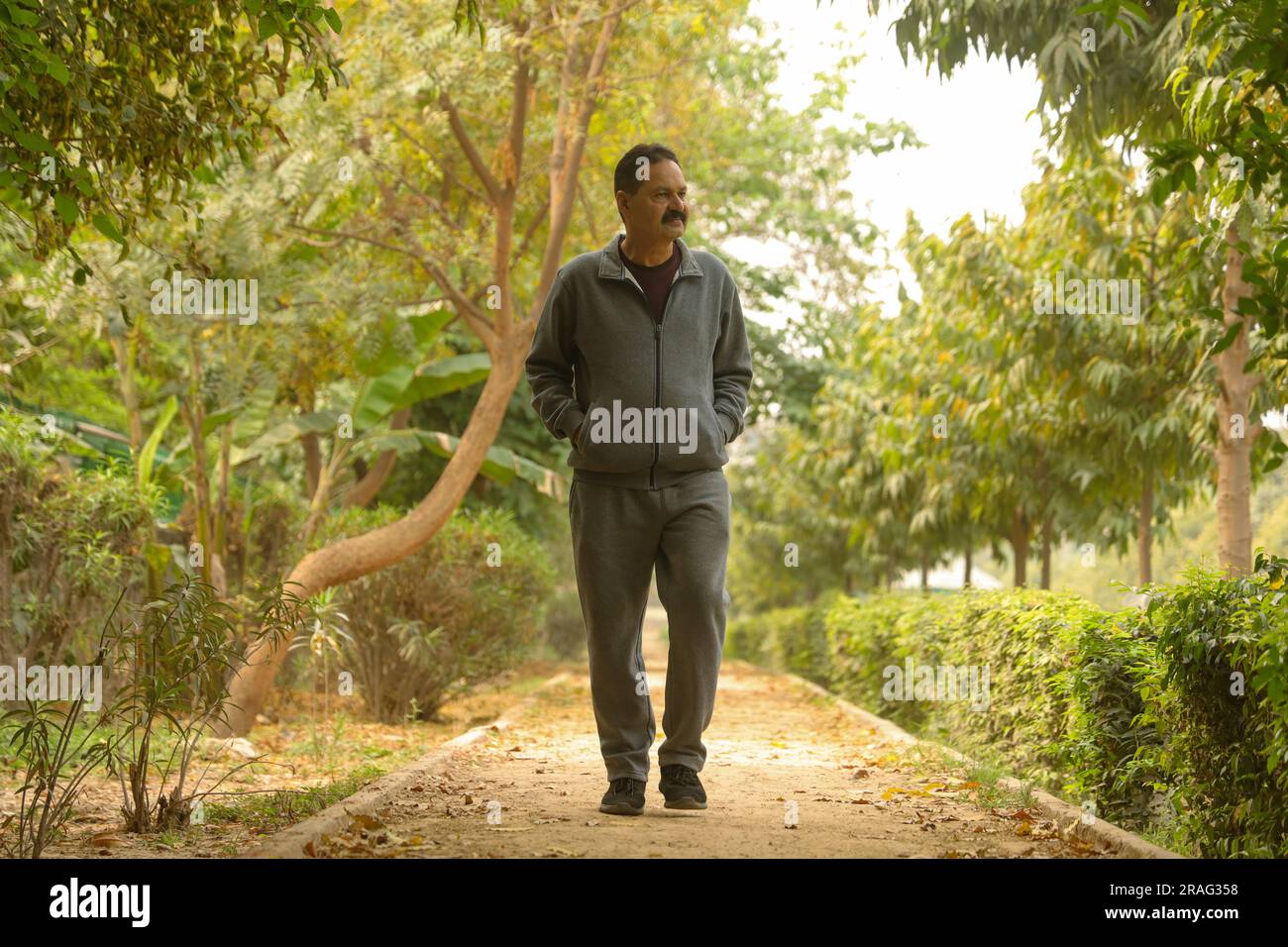 Happy Indian Old man jogging in the park on a Jogging track and trail ...