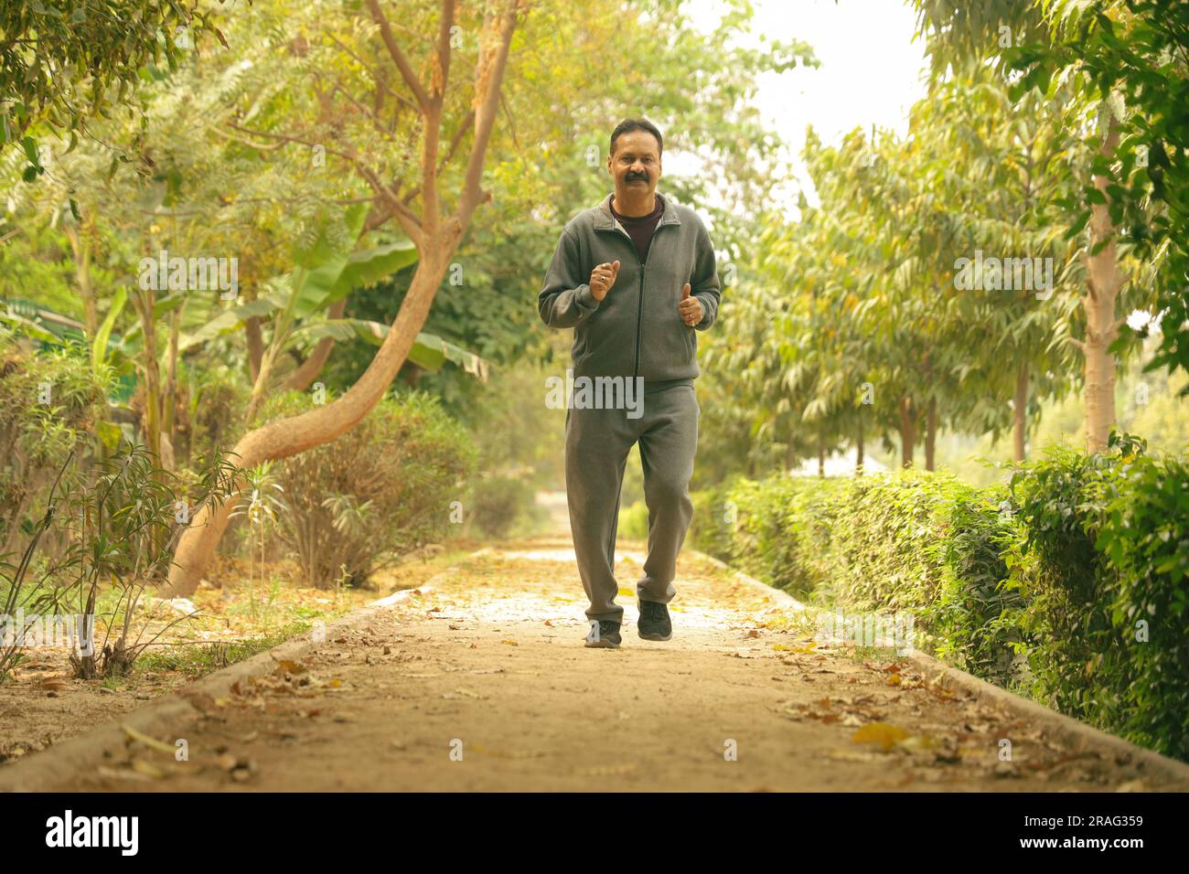 Happy Indian Old man jogging in the park on a Jogging track and trail ...