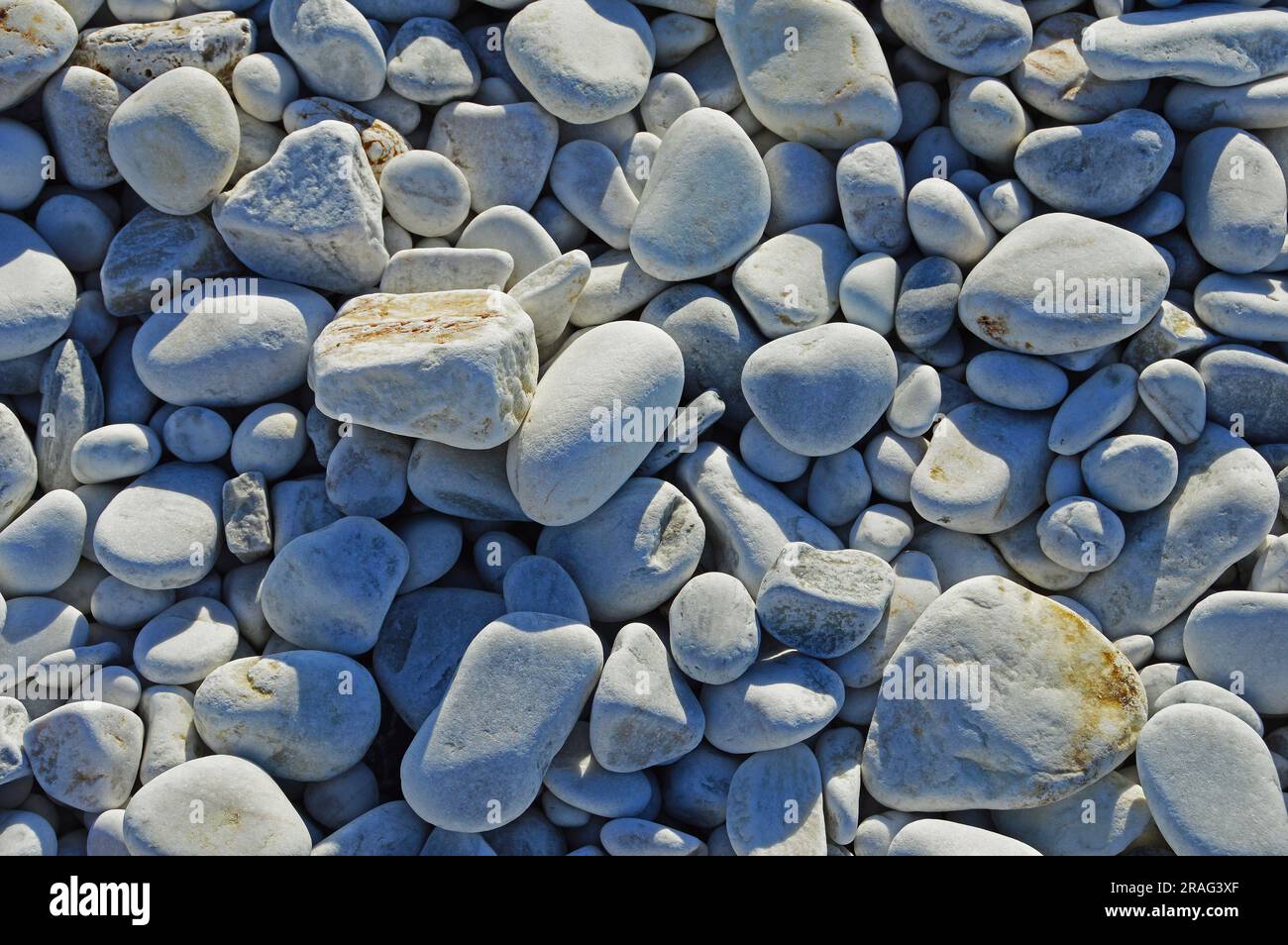 Different sized oval and round marble pebbles on the coast of the ...
