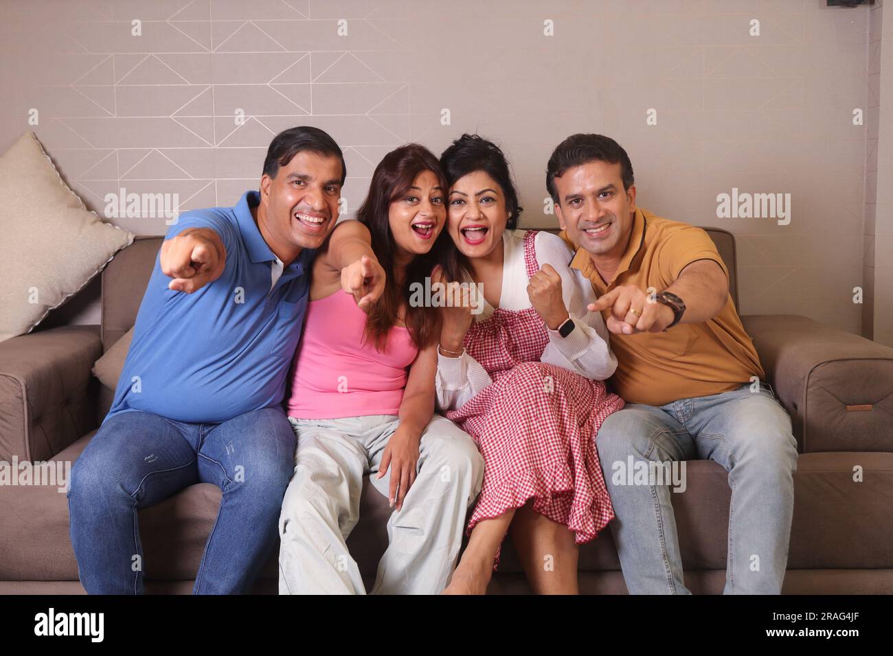 Happy Indian friends couples sitting on a couch enjoying watching match ...