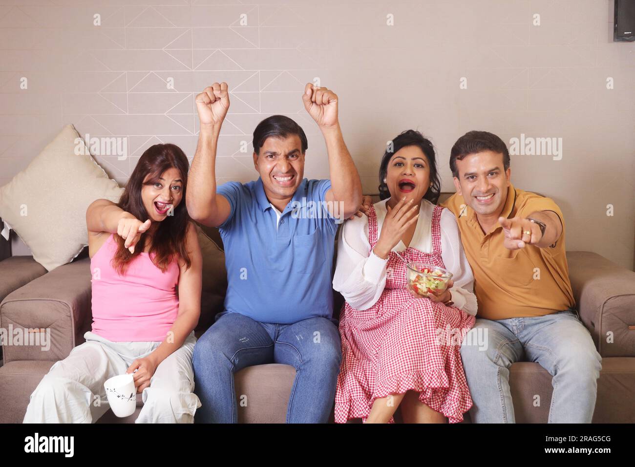 Happy Indian friends couples sitting on a couch enjoying watching match ...