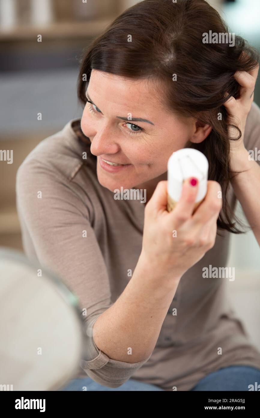 beautiful woman applying hair spray Stock Photo - Alamy