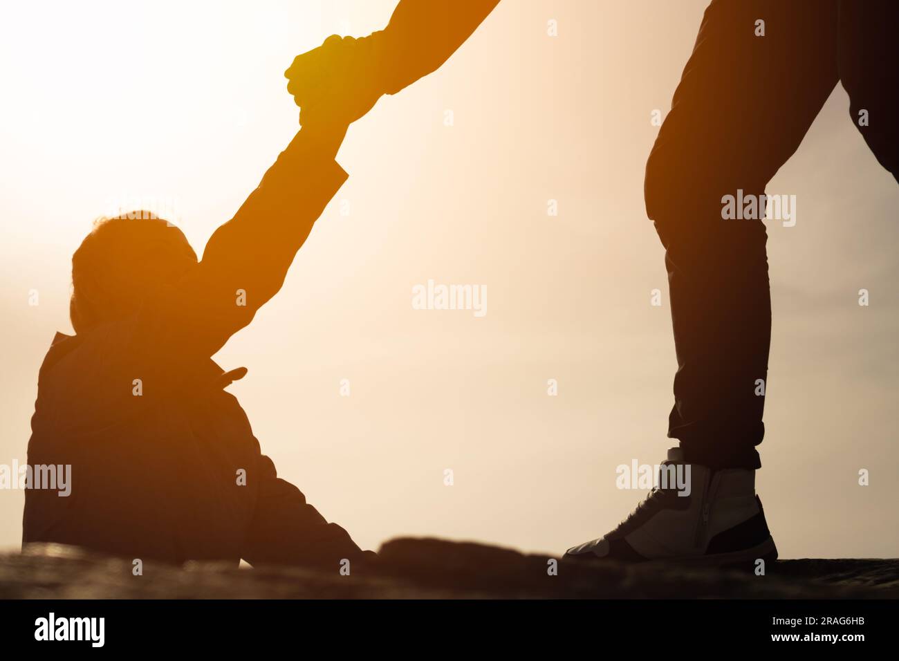 Giving a helping hand. Man helping female climber up a mountain ...
