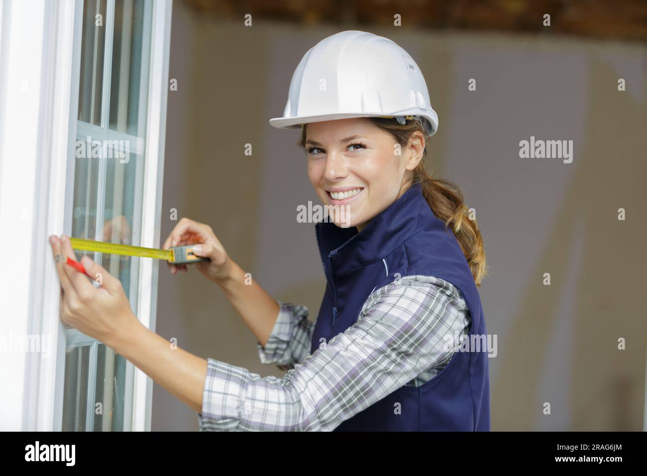female builder measuring window from the exterior Stock Photo - Alamy