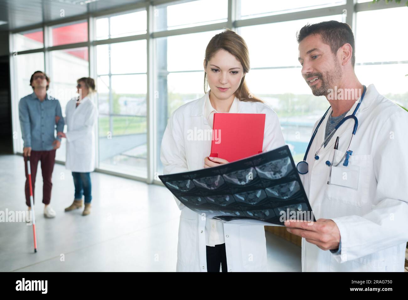 doctors looking at xray medic helping blind man in background Stock Photo - Alamy