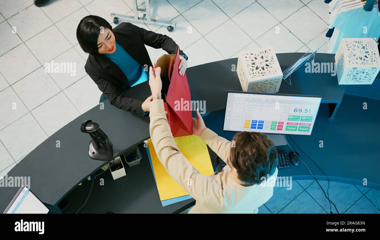 Asian client taking shopping bags paying for clothes, making purchase ...