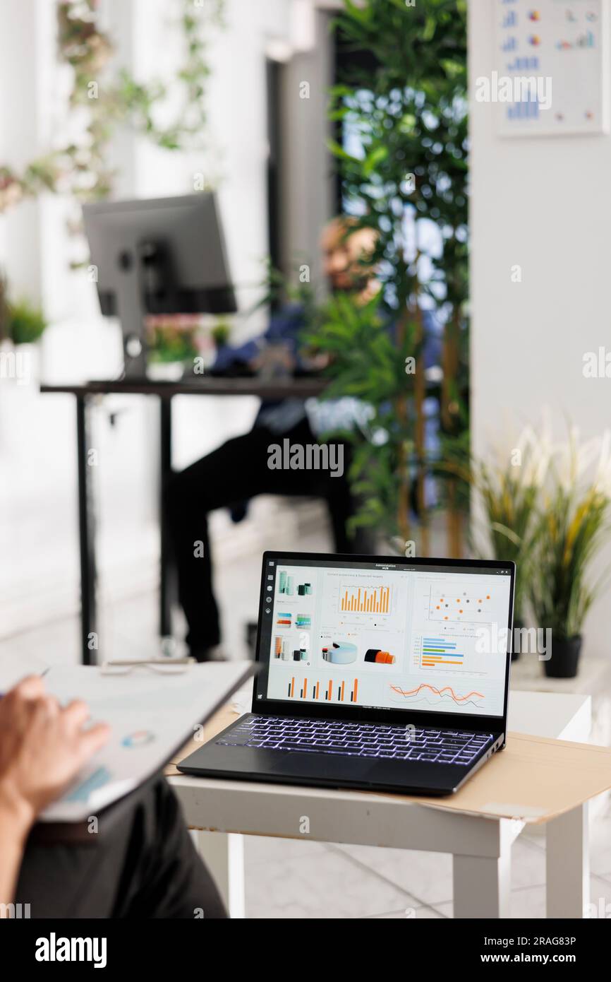 Employee reviewing sales data on laptop screen and budgeting strategy ...