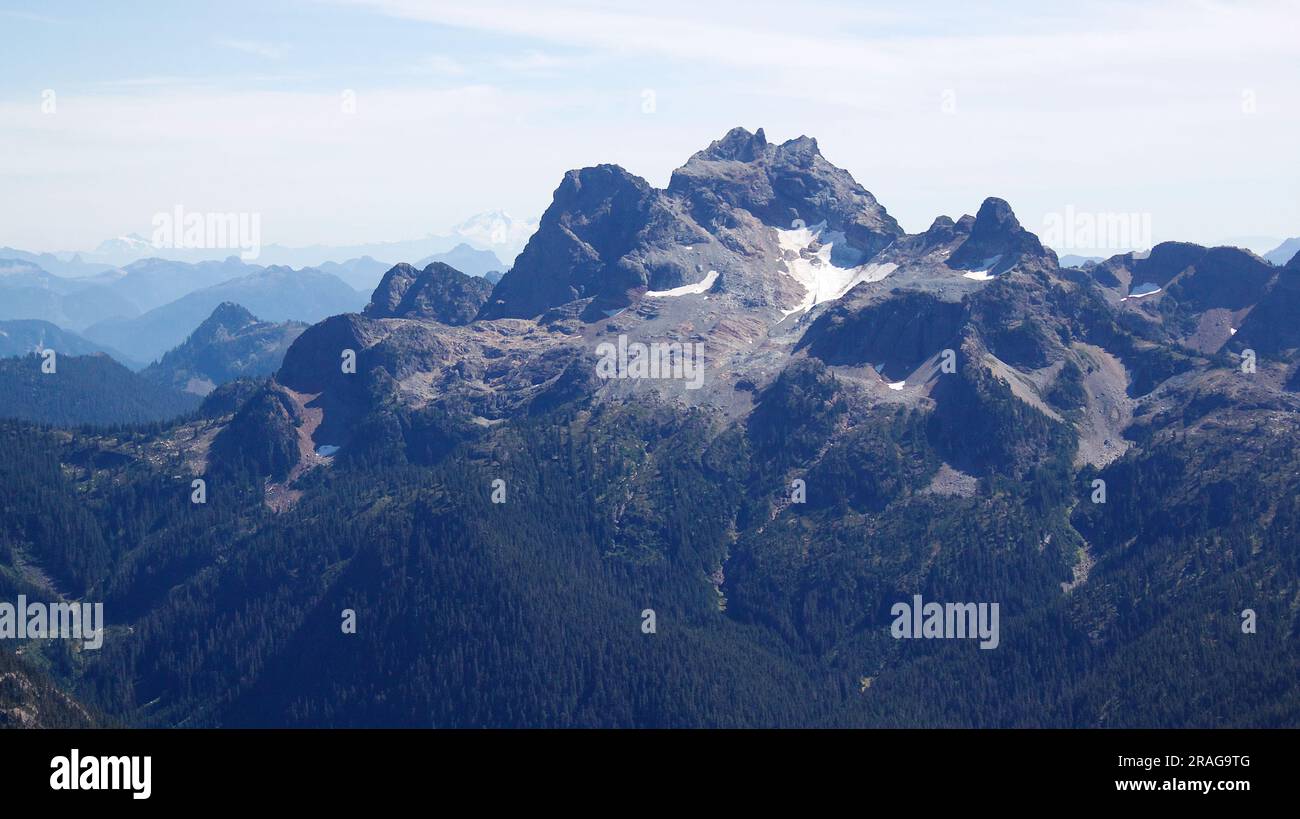 The peak of a mountain surrounded by evergreen trees. In British ...