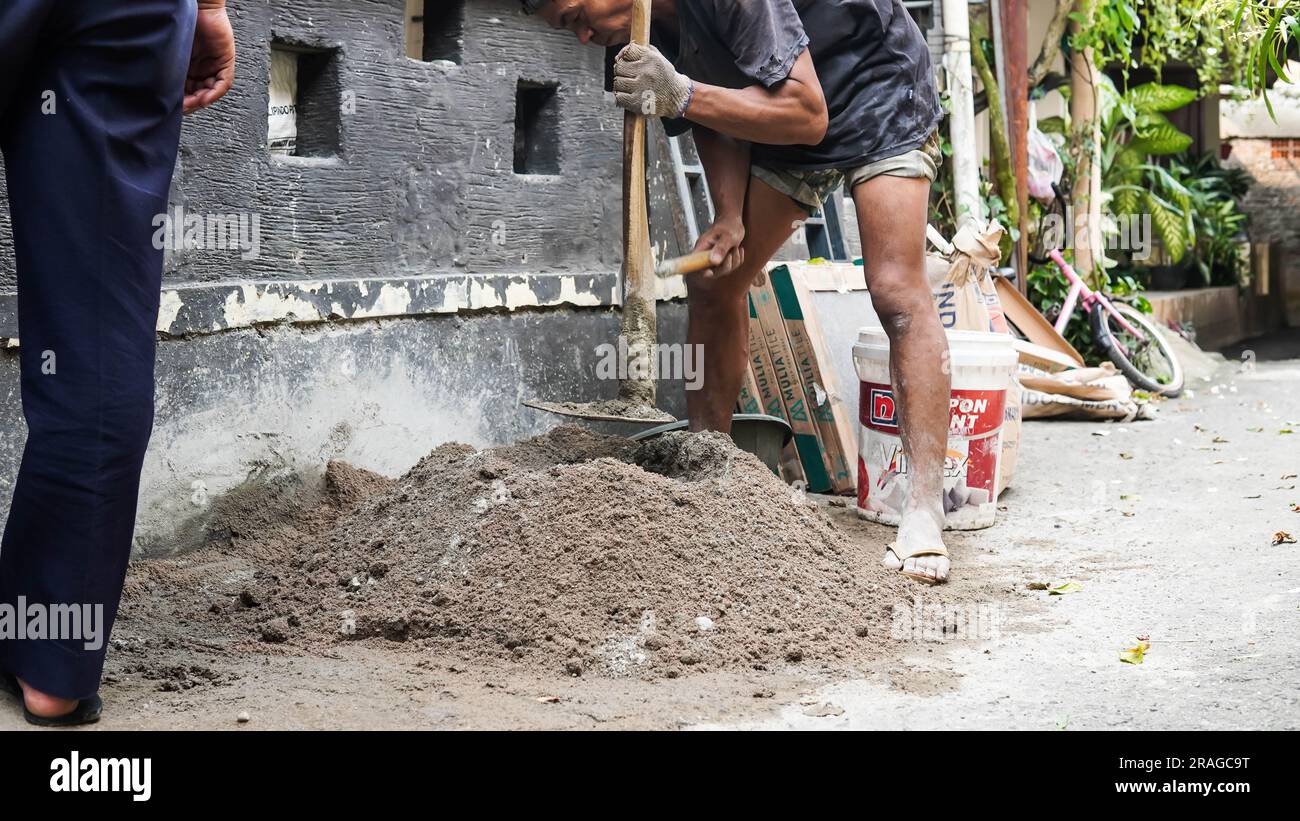 Asian worker using hoe for mixing cement power with sand Stock Photo ...