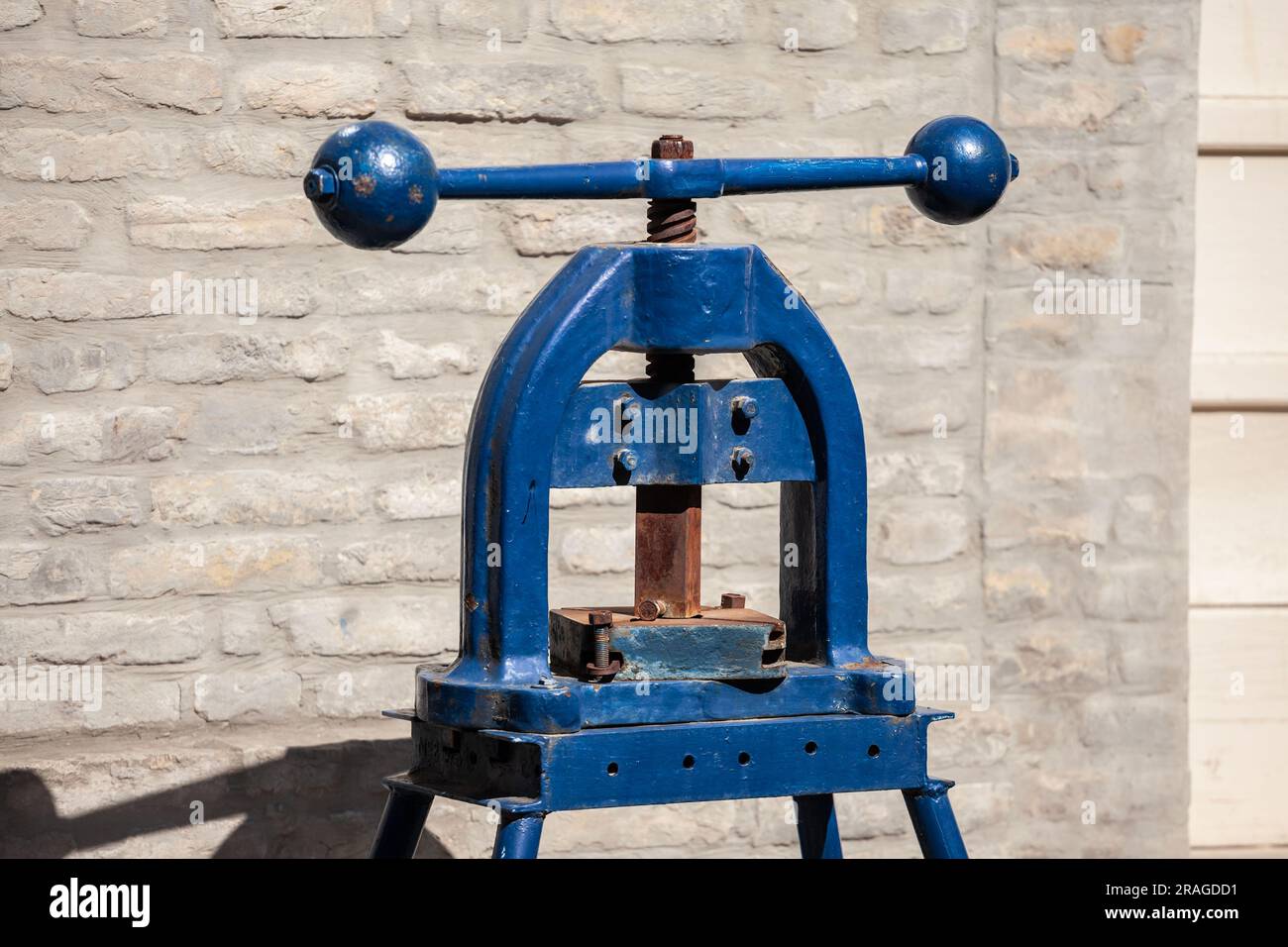 Picture of a manual printing press on display on a brick wall. A ...