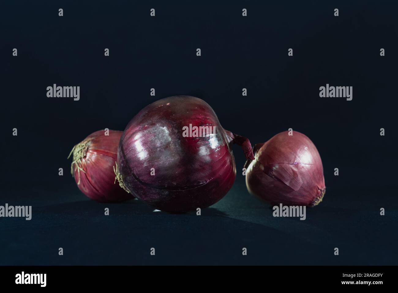 Picture of three red onions isolated on a black background. Red onions ...