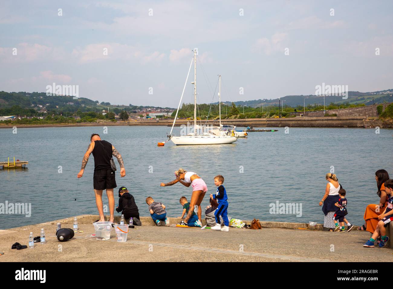 Families enjoying a day at the seaside fishing for crabs off the ...