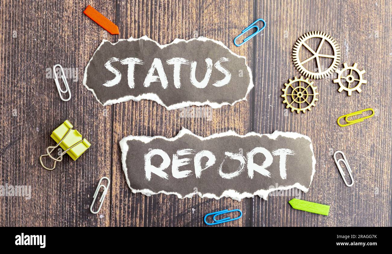 On a light colored office table with the text Status Report. Business ...