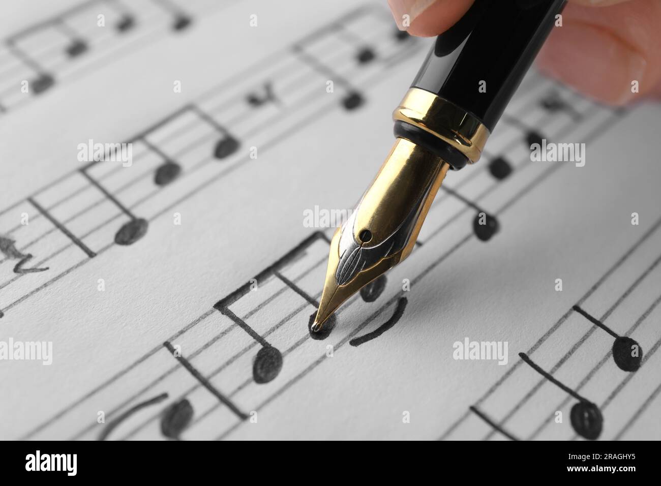 Woman writing musical notes with fountain pen on sheet of paper ...