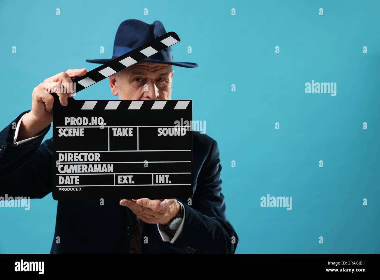 Senior actor holding clapperboard on light blue background, space for ...