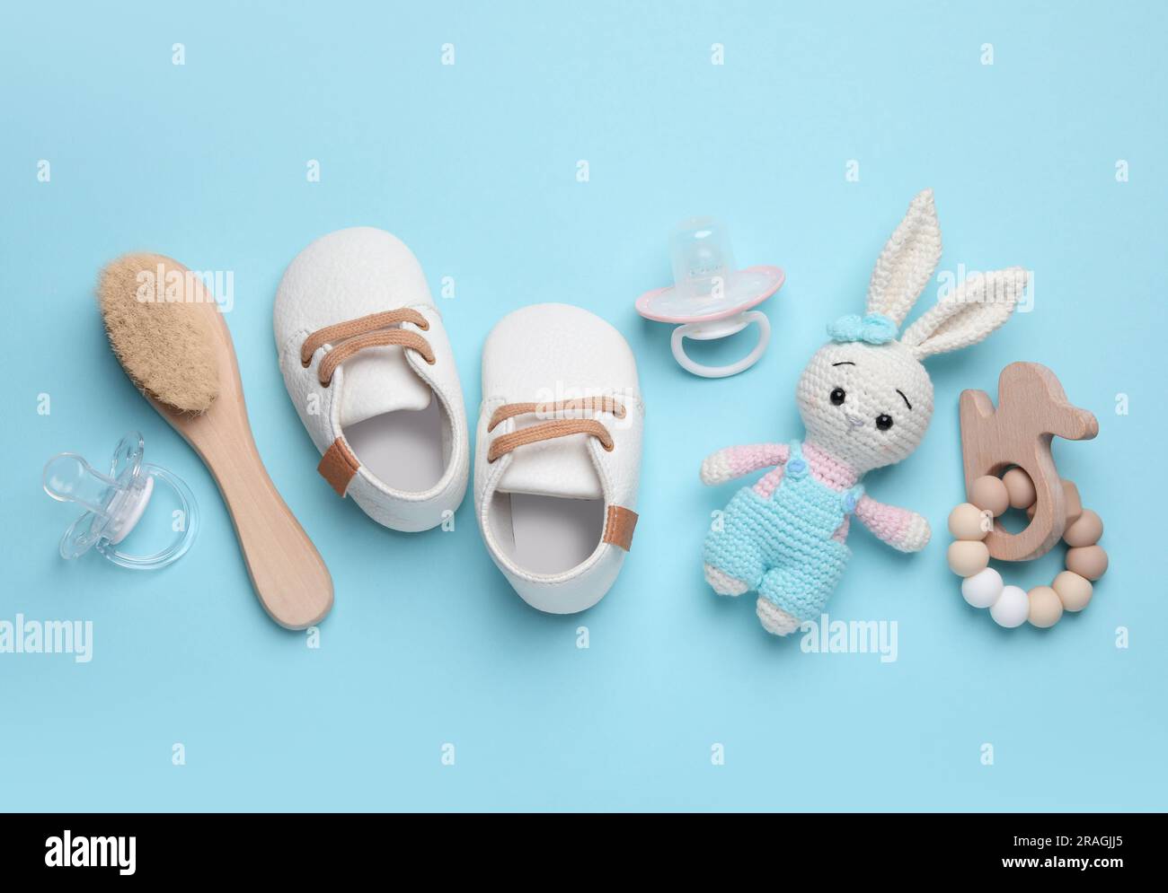 Flat lay composition with pacifiers and other baby stuff on light blue ...