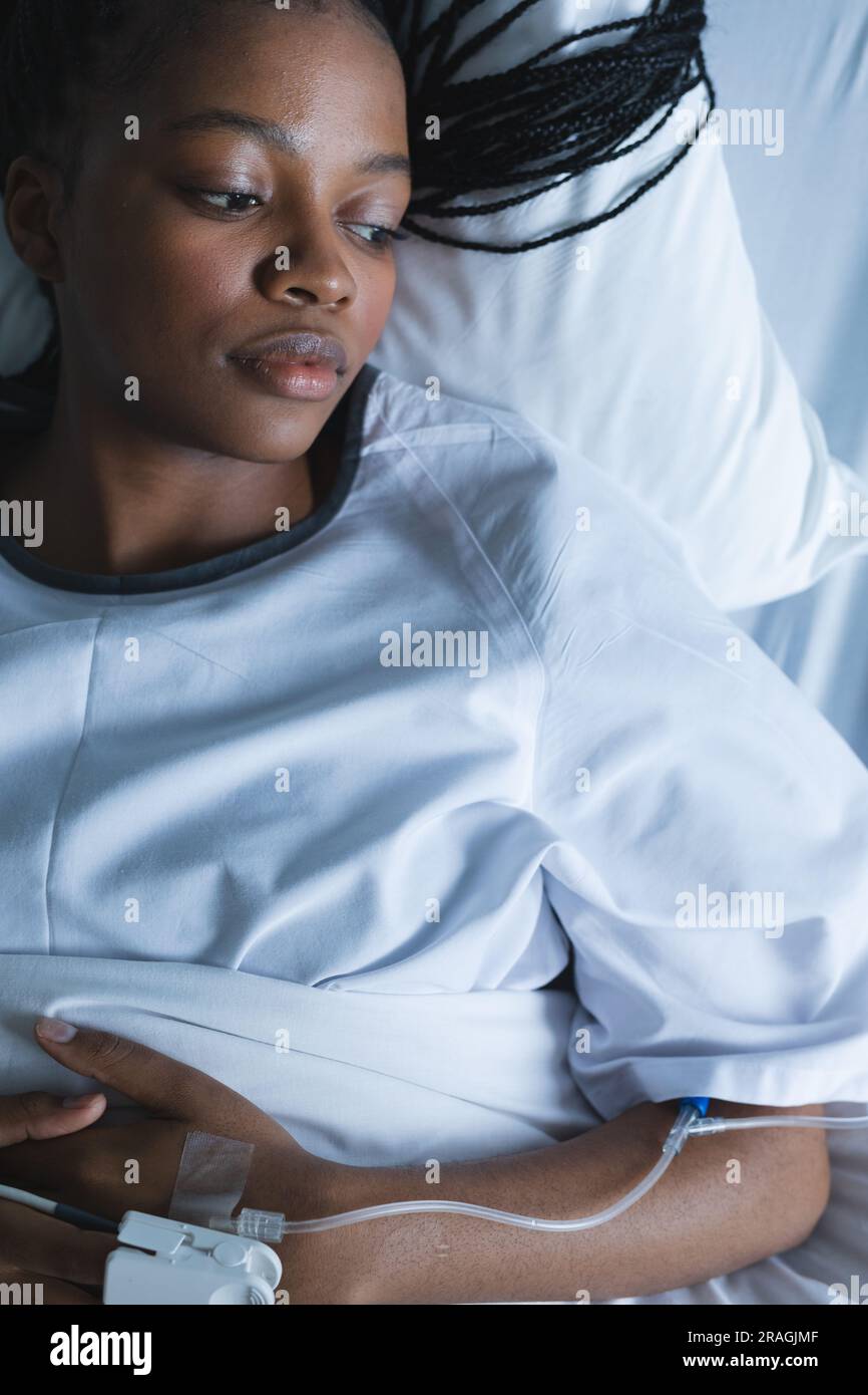 African American Female Patient With Drip On Hand Lying On Bed In