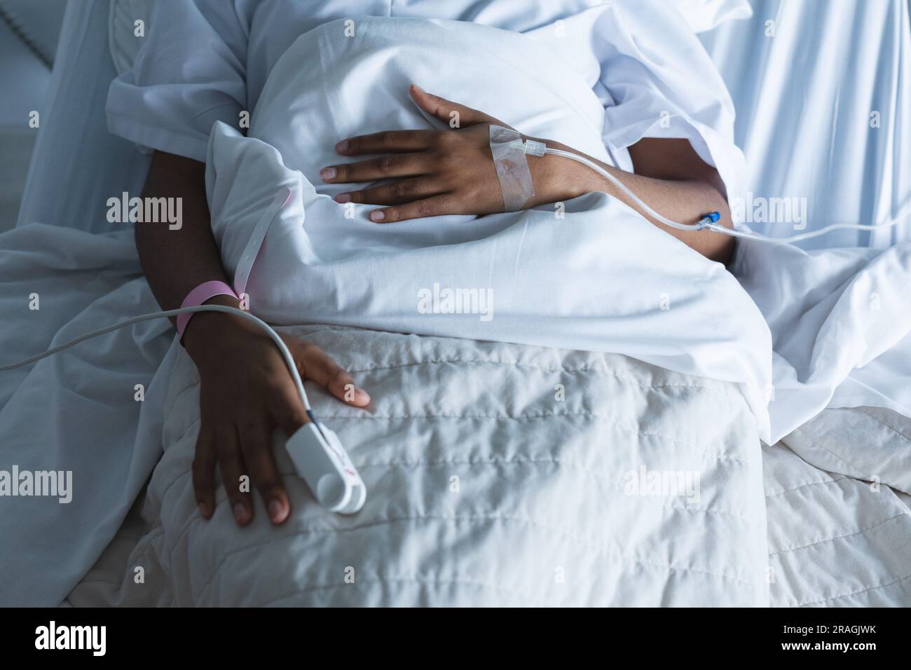 Midsection of african american female patient with drip on hand, lying ...