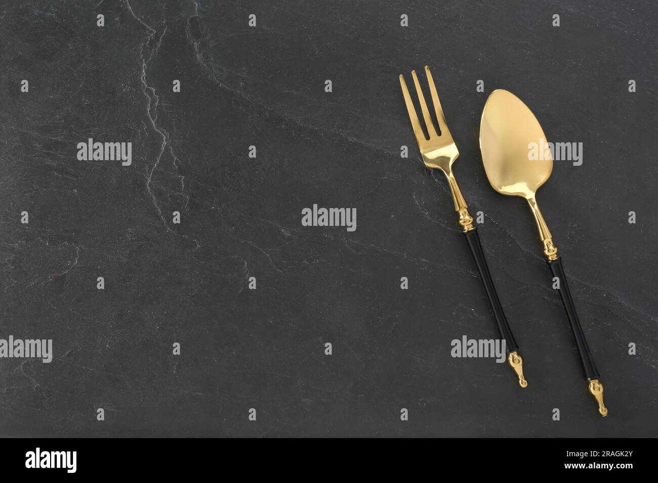 Shiny fork and spoon on black table, flat lay. Space for text Stock ...