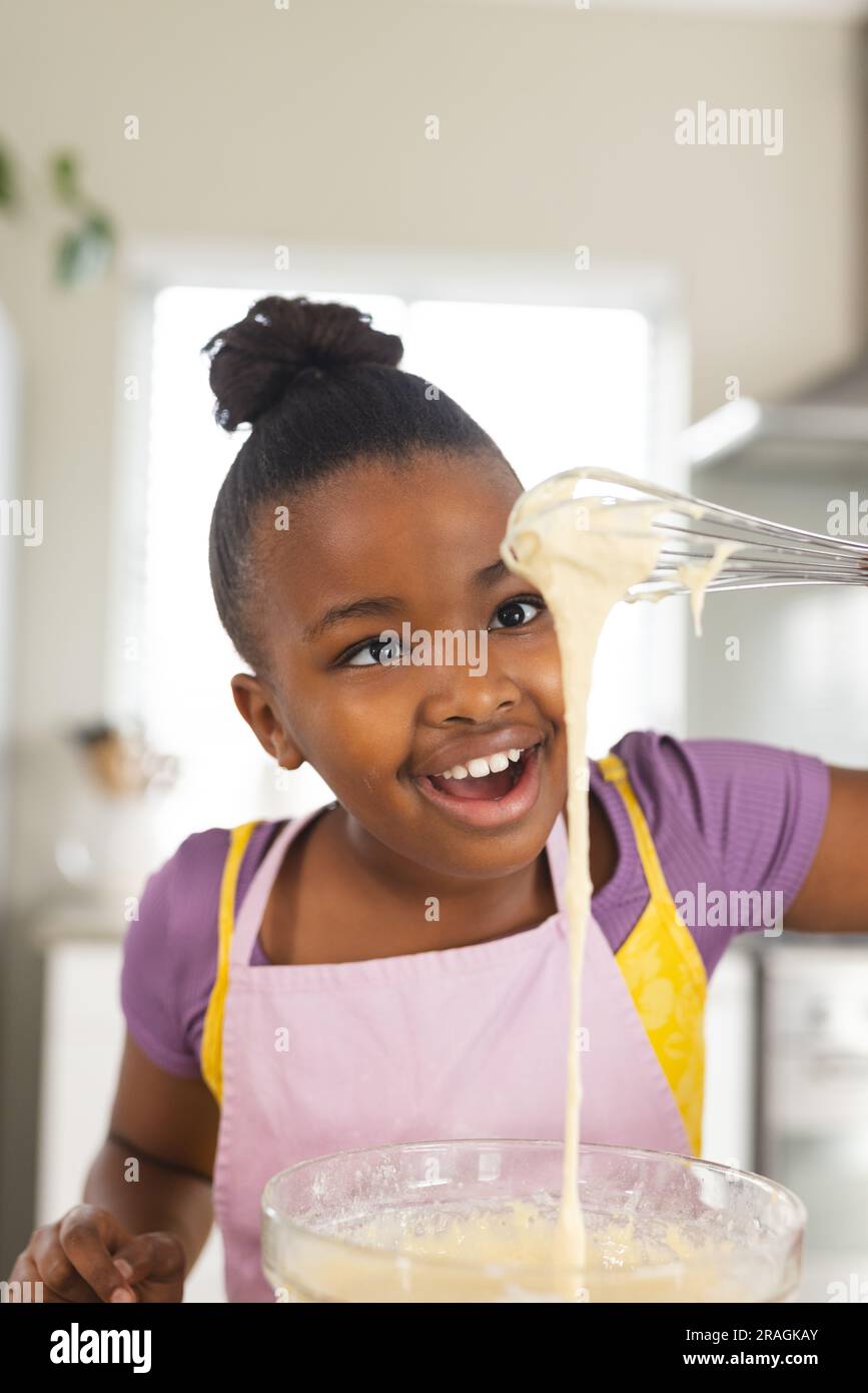Happy african american girl baking cupcakes, mixing ingredients in bowl ...