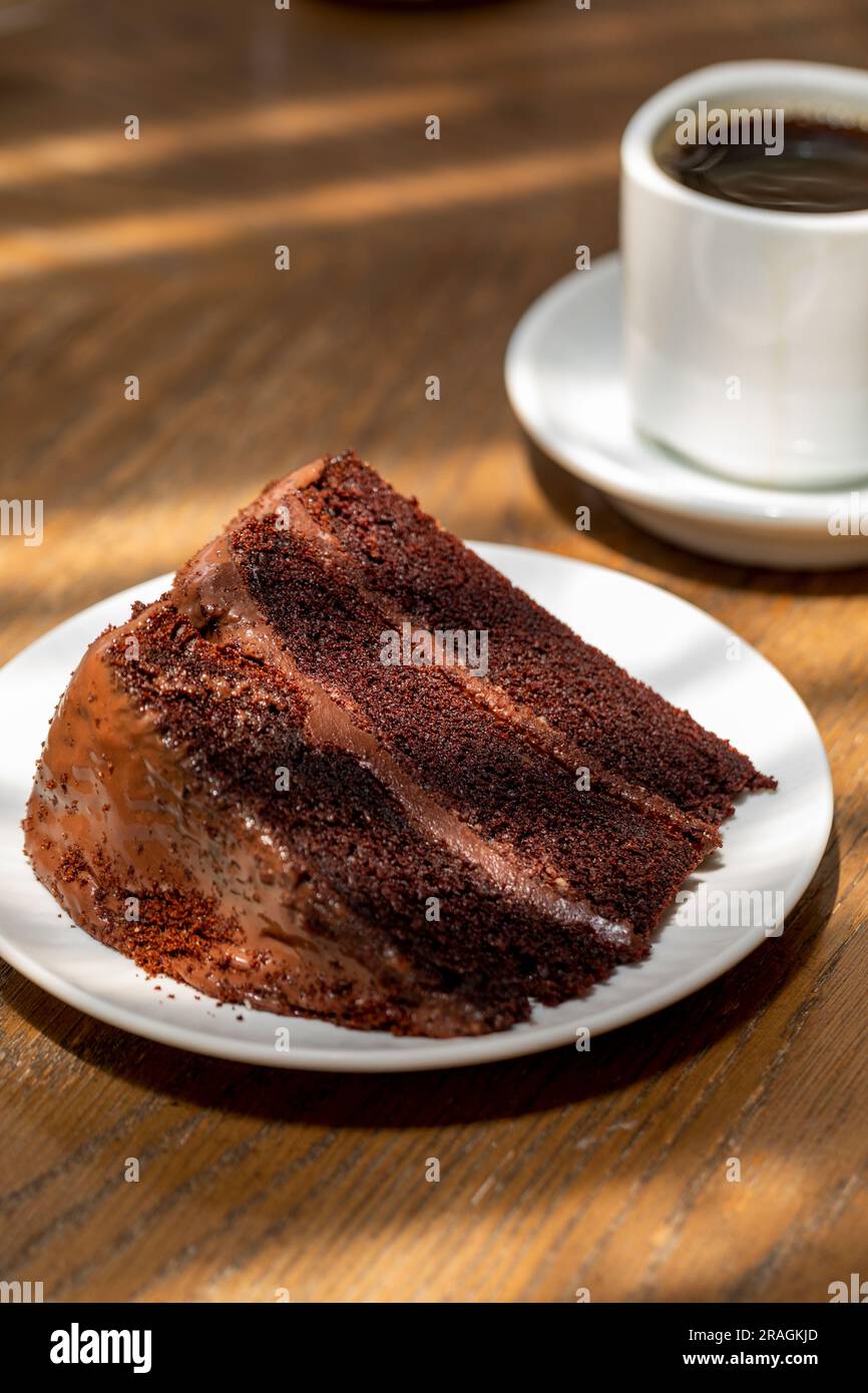 chocolate cake cut is a big slice with a cup of coffee on the back ...