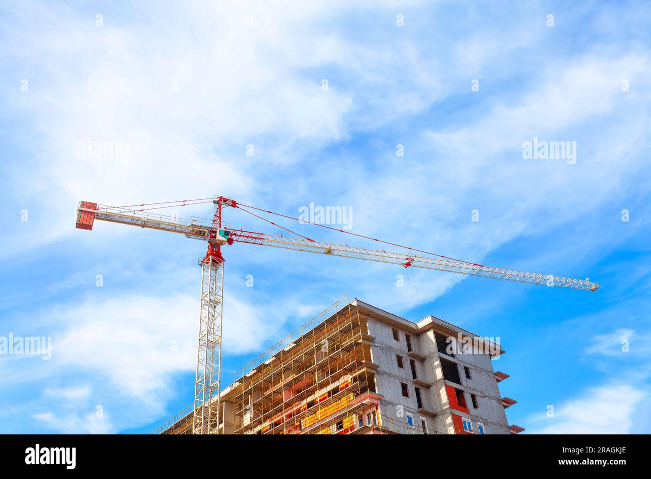 Crane and building under construction against blue sky with white ...